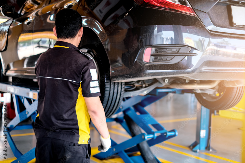 car automobile mechanic working on repairing the wheel tire of vehicle ...