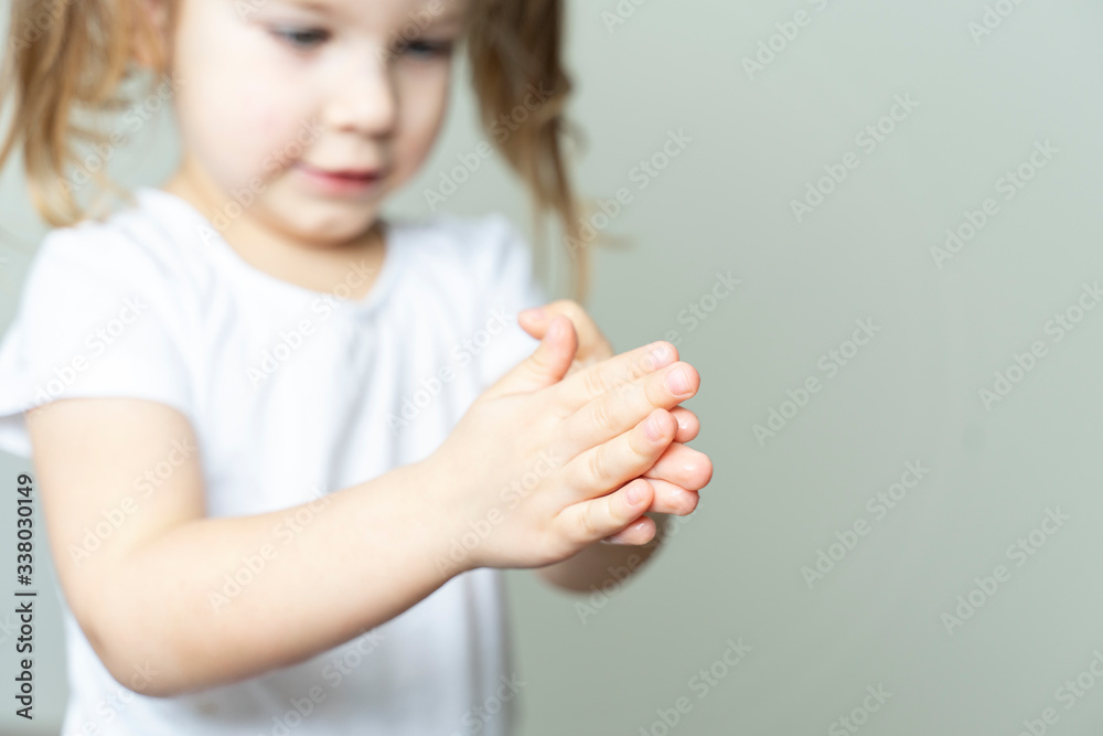 little girl 4 years old in a white T-shirt rubs the sanitizer on her ...