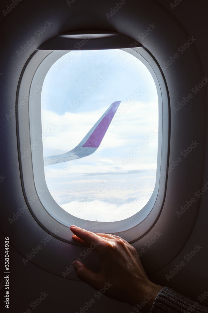 Woman looks out the window of an airplane. Hand near the porthole. Girl ...