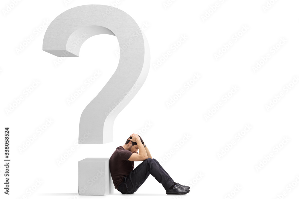 Sad young man sitting on the floor holding his head and leaning against ...