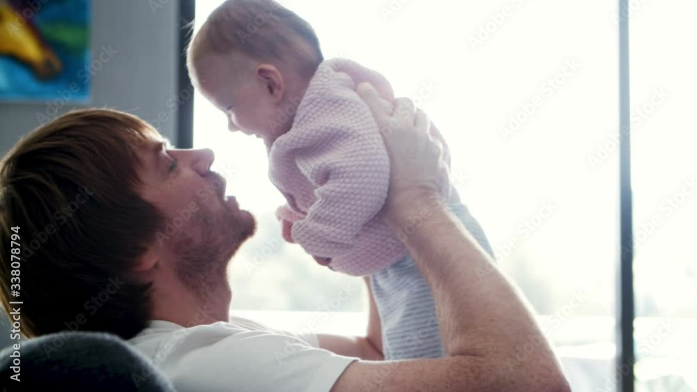 Happy dad holding baby daughter in air. New father nursing little six ...
