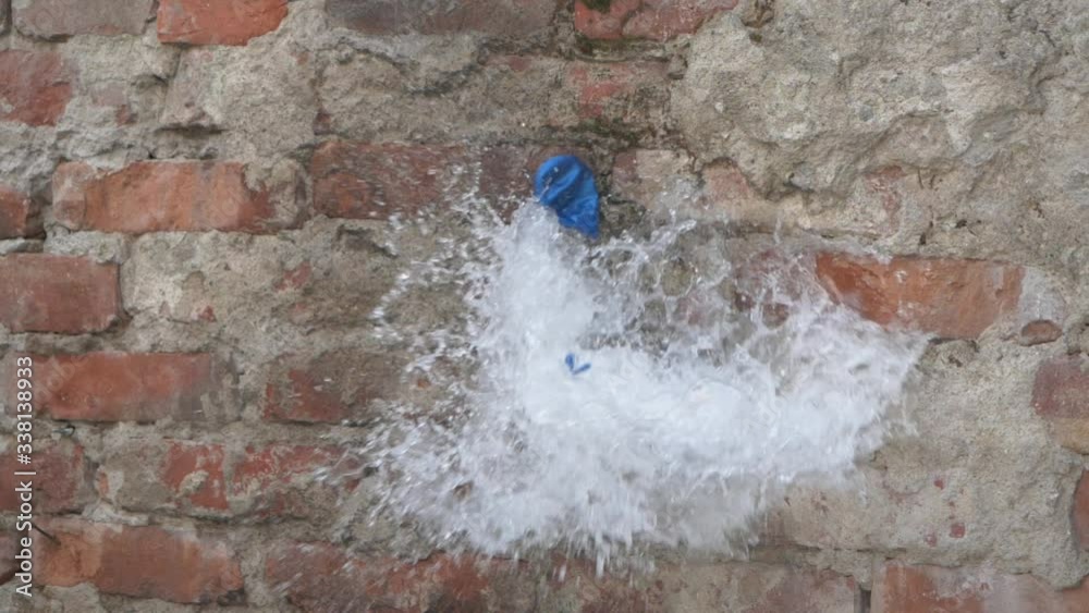 Blue Rubber Water Balloon Gets Thrown At A Brick Wall And Pops Stock ...