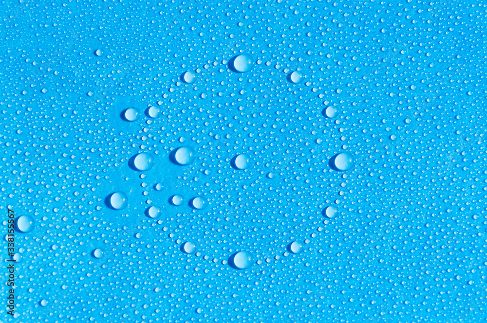 Drops of water in the form of a dial are scattered on a wet blue ...