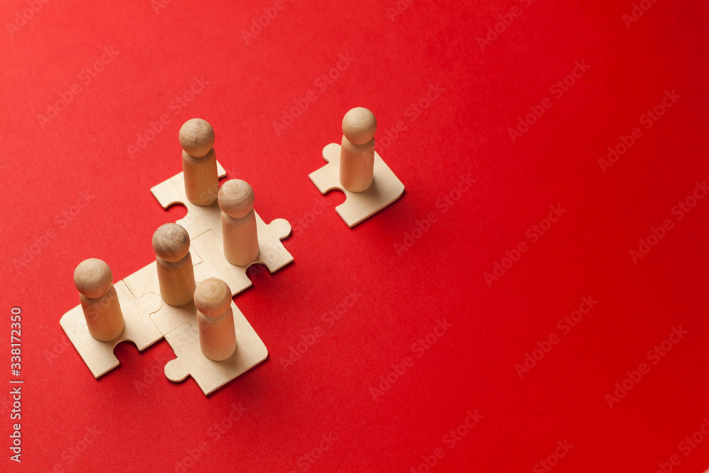 Wooden figures on puzzles on red background as a symbol of team ...
