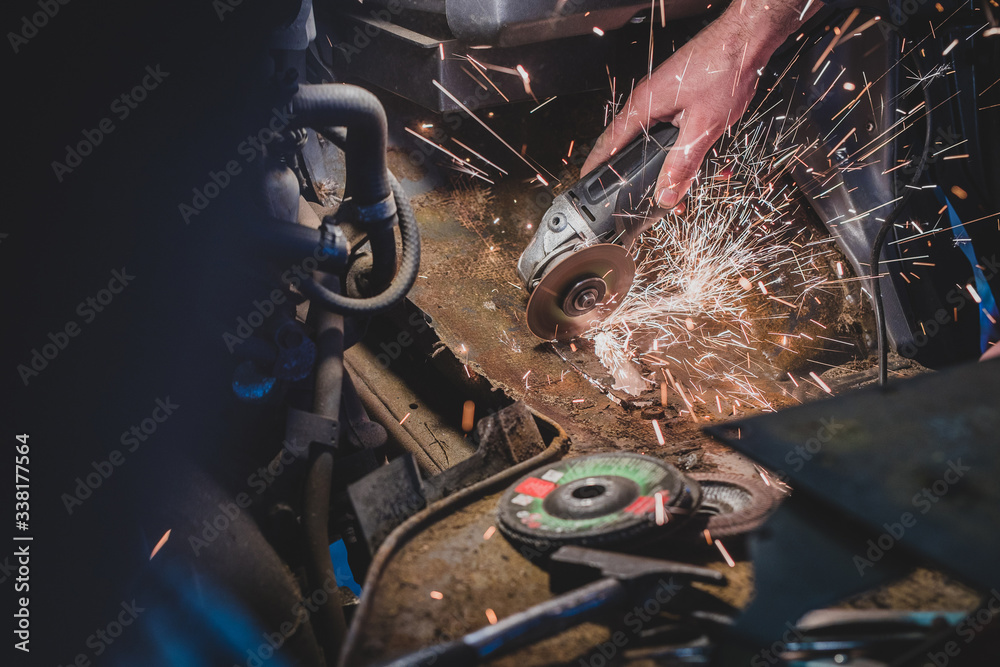 Bare hands of a man using an angle grinder to cut off the excess rusty ...