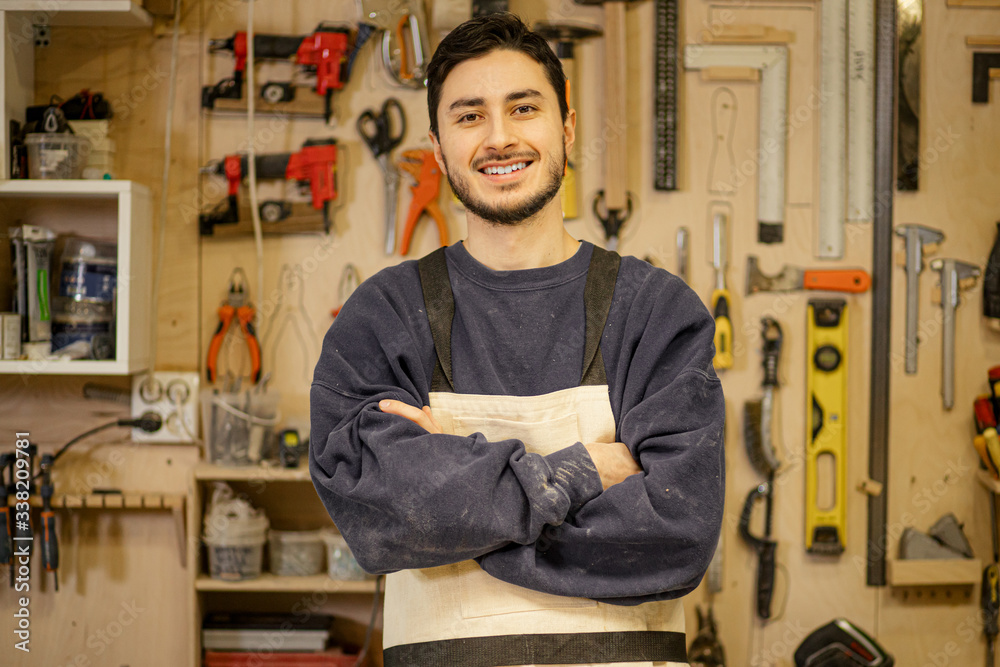portrait of young caucasian positive carpenter at work place, handsome ...