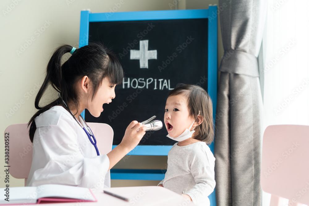 Two Asian cute girls pretend to be doctor and patient. Young doctor ...