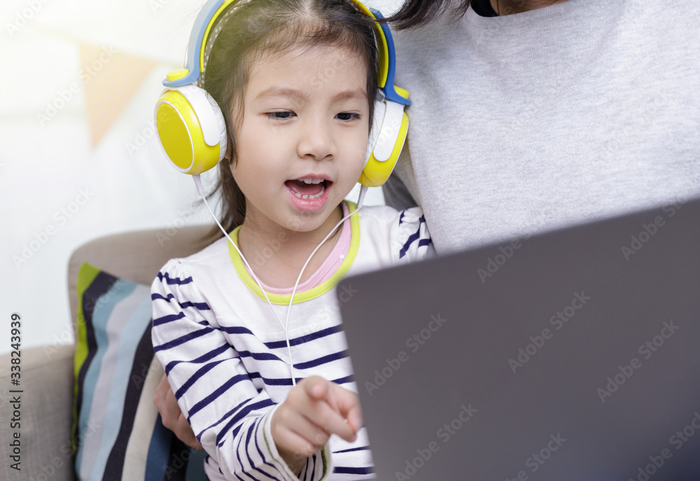 Asian little child girl learning at home with laptop computer using ...