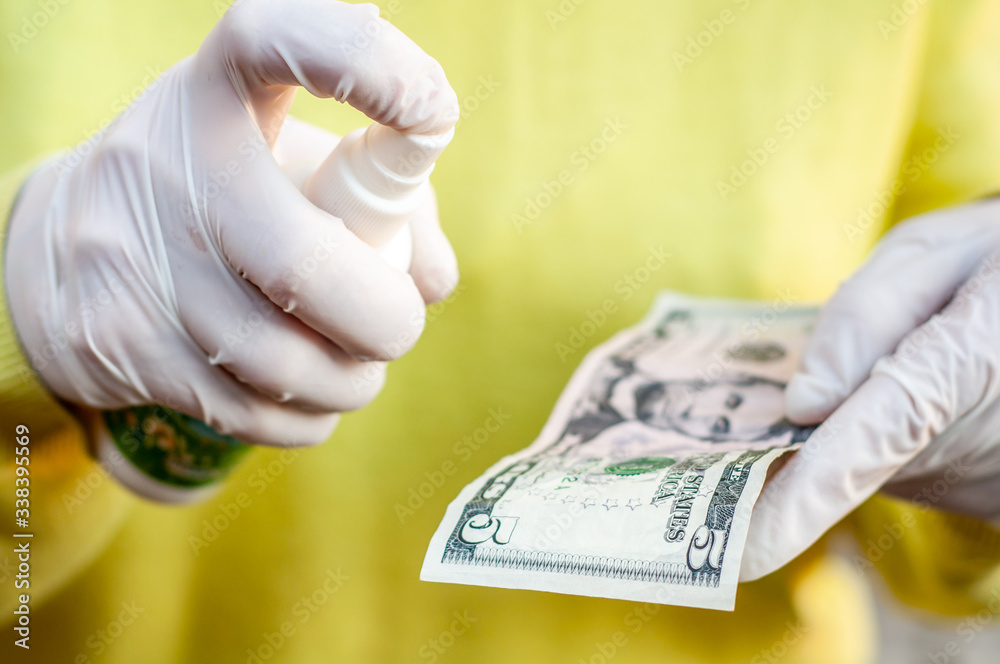 Disinfection of money. Hands in white medical gloves are spraying ...
