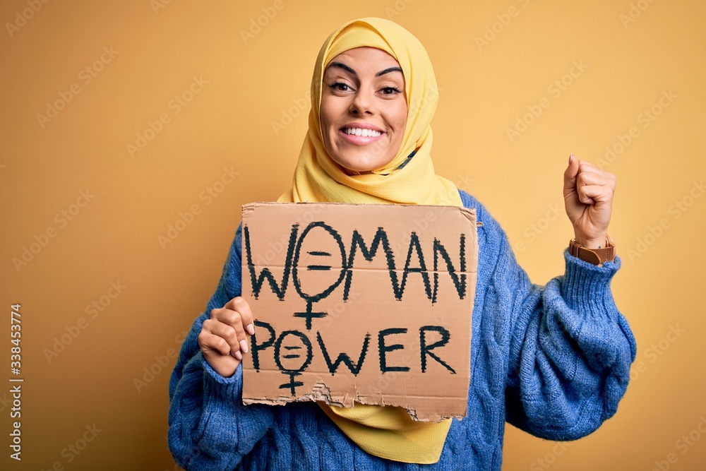Young beautiful arab woman wearing islamic hijab holding banner with ...