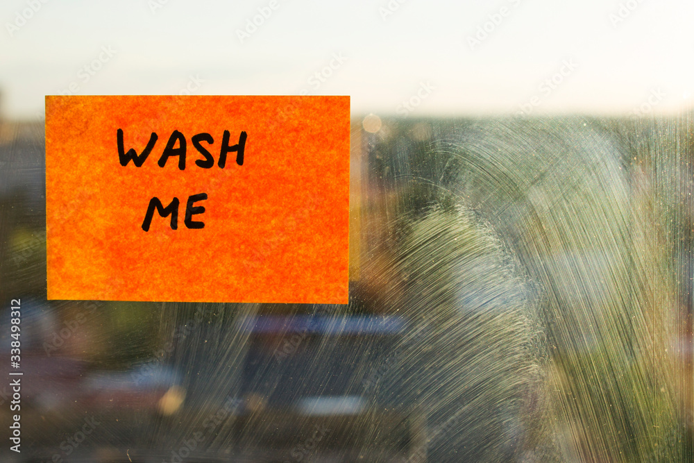 Wash me, inscription on pasted note, dirty window in the mud stains. A ...