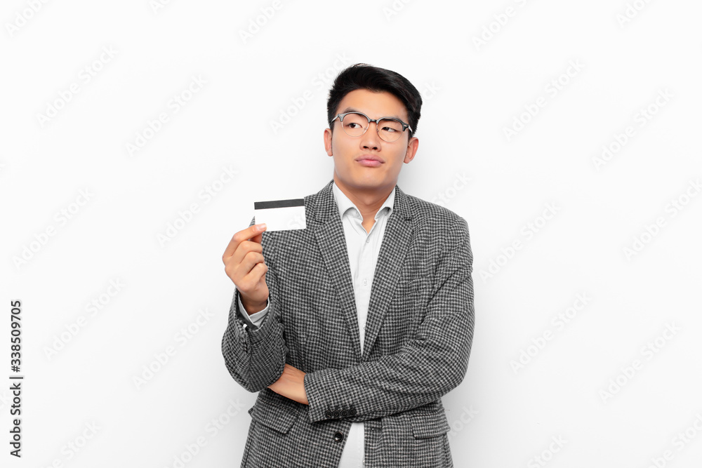 young japanese man shrugging, feeling confused and uncertain, doubting ...