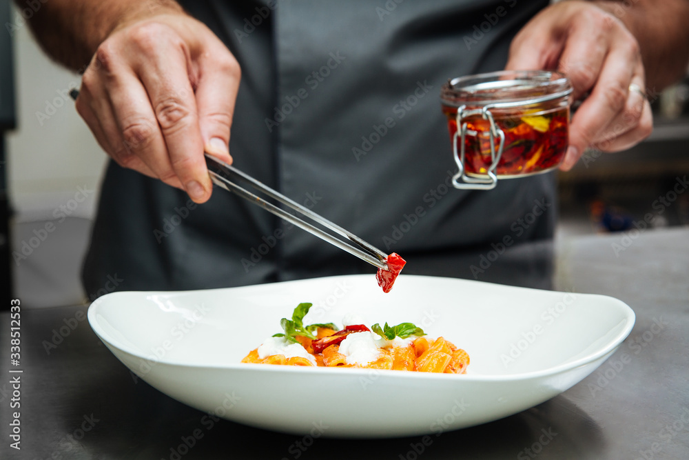 Chef hand cooking pasta penne with mozzarella cheeze and sun-dried ...