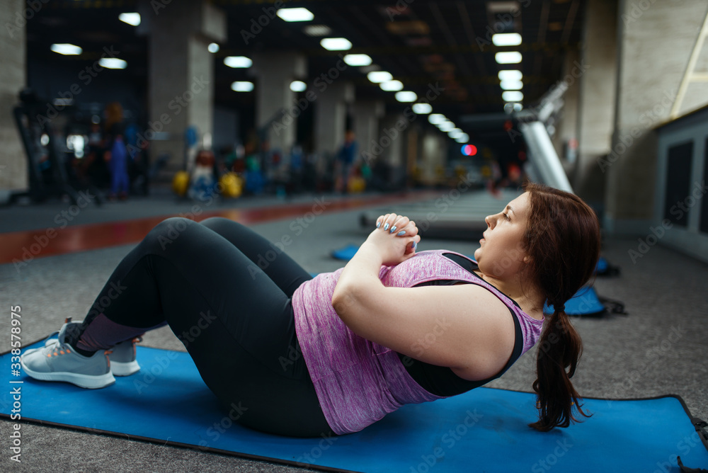 Overweight woman doing exercise on mat in gym Stock Photo | Adobe Stock