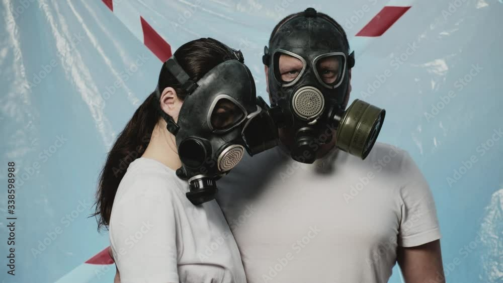 young people in gas masks stand against a background of a fenced ...