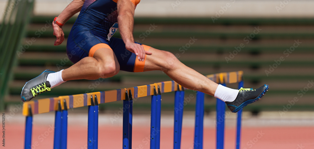 Athlete running a hurdle race in a stadium, runner jumping over an ...