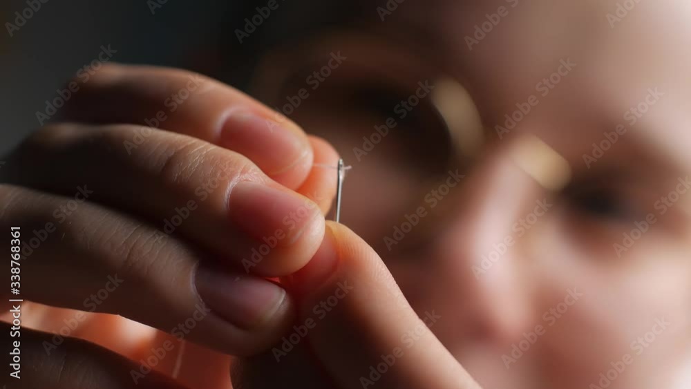 Threading the eye of a needle. Pulling the thread into the needle eye ...