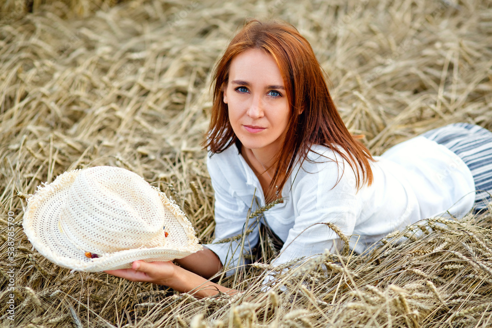 Girl lying in a wheat field and posing on hay dry grass, summer season ...
