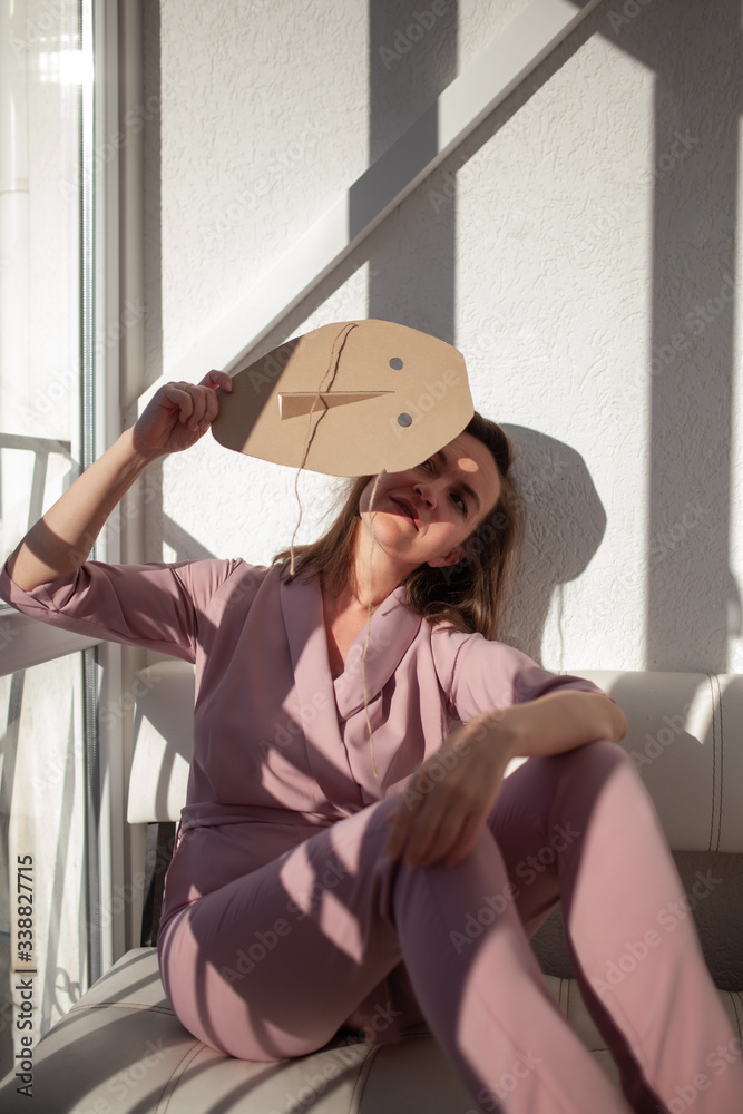 Portrait of a woman. A female hides his face behind a cardboard mask ...