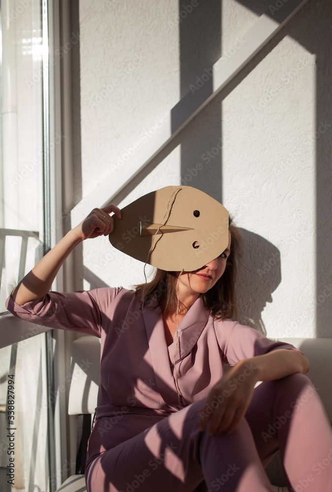 Portrait of a woman. A female hides his face behind a cardboard mask ...