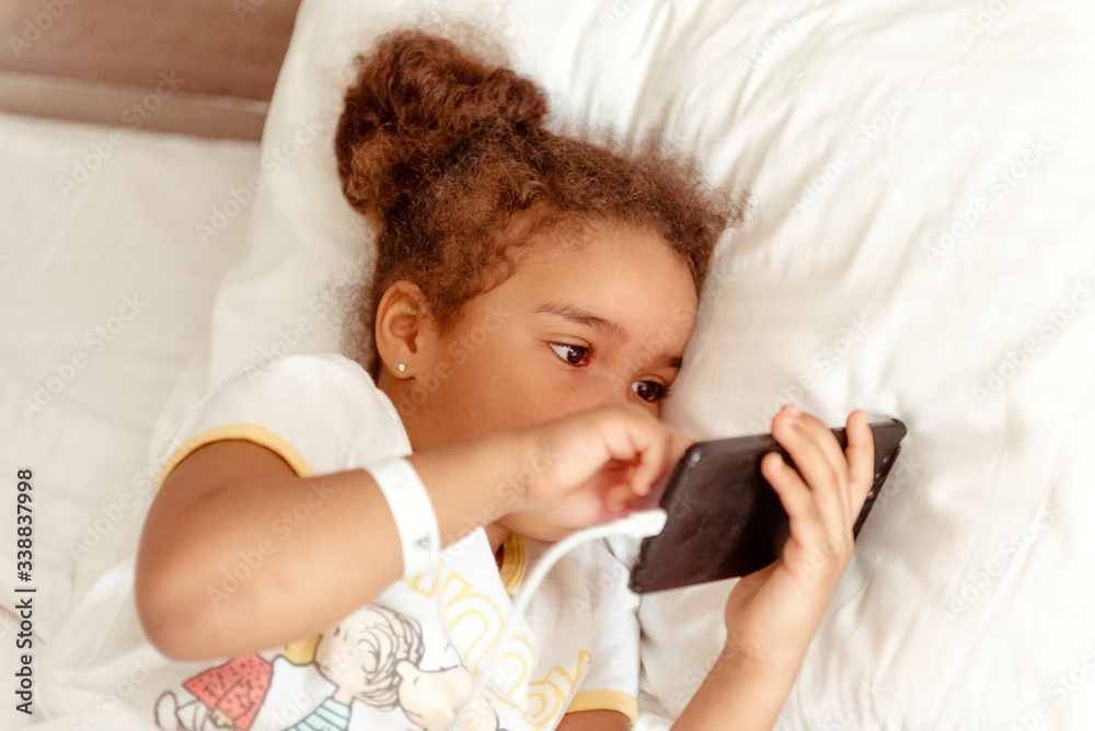 Cute little kid girl watching video on smartphone with smiley face ...