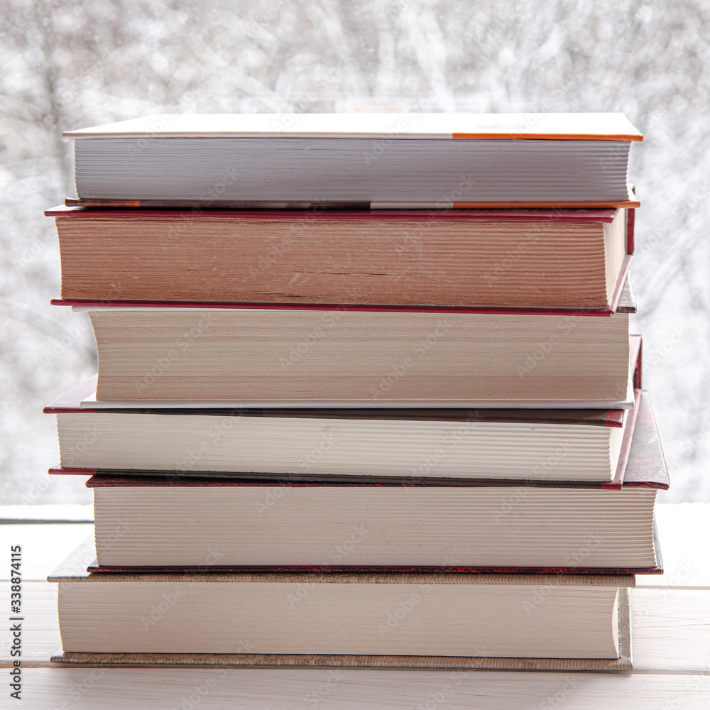 Book stack on wood desk and blurred bookshelf in the library room ...