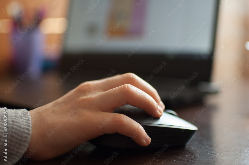 Little child hand is holding a computer mouse on laptop screen ...