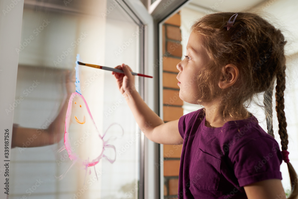 Self-isolation at home. Child quarantined girl paints a rainbow on a ...