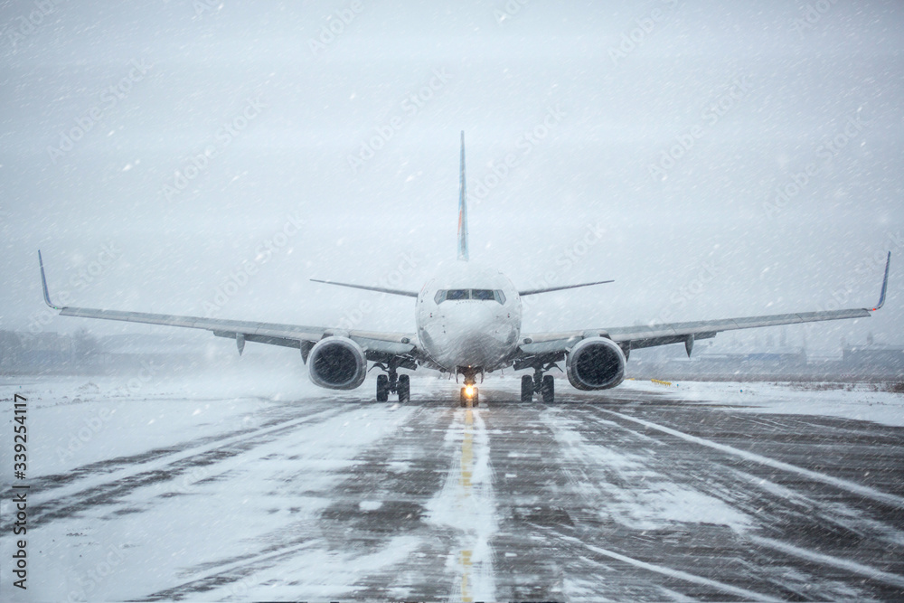 Airliner on runway in blizzard. Aircraft during taxiing during heavy ...