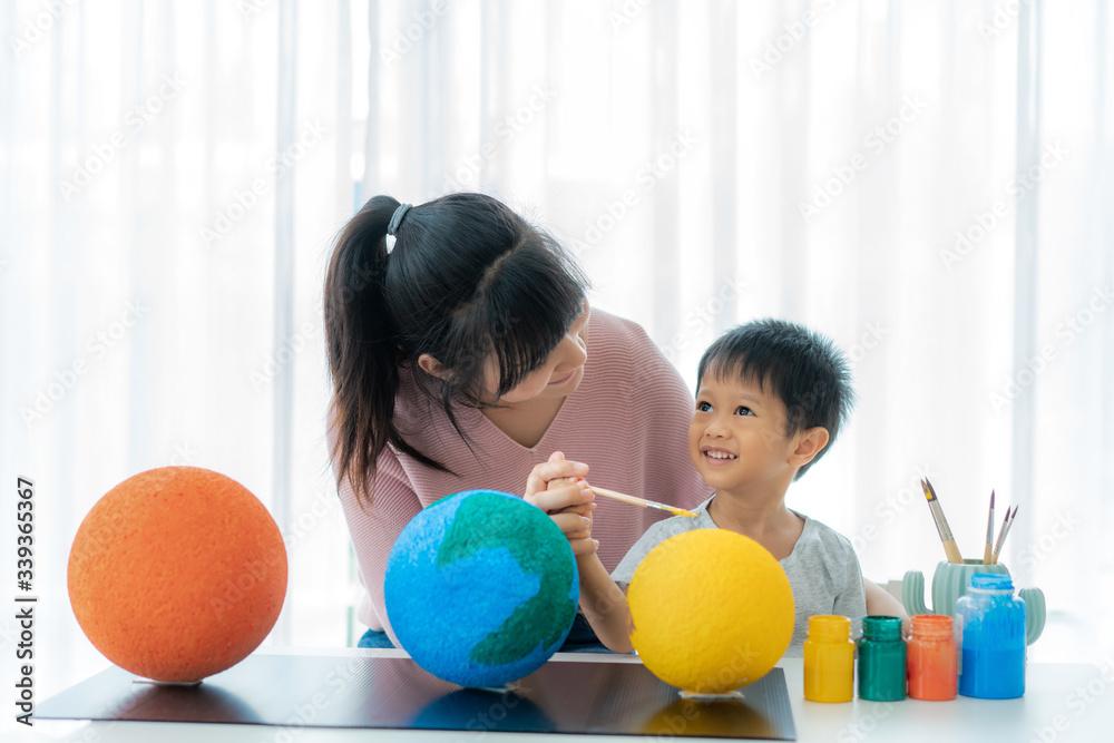 Asian preschool student boy with mother painting the moon learning about the solar system at ...