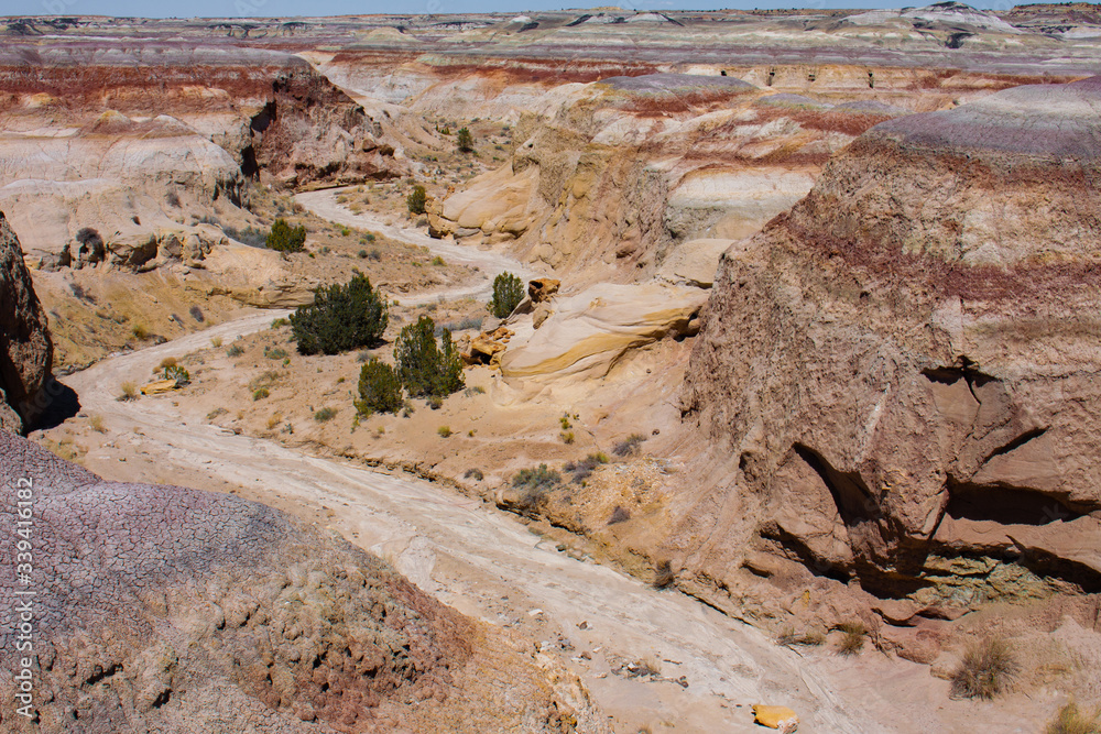 Dry riverbed trail between canyons with layered mineral deposits in the ...