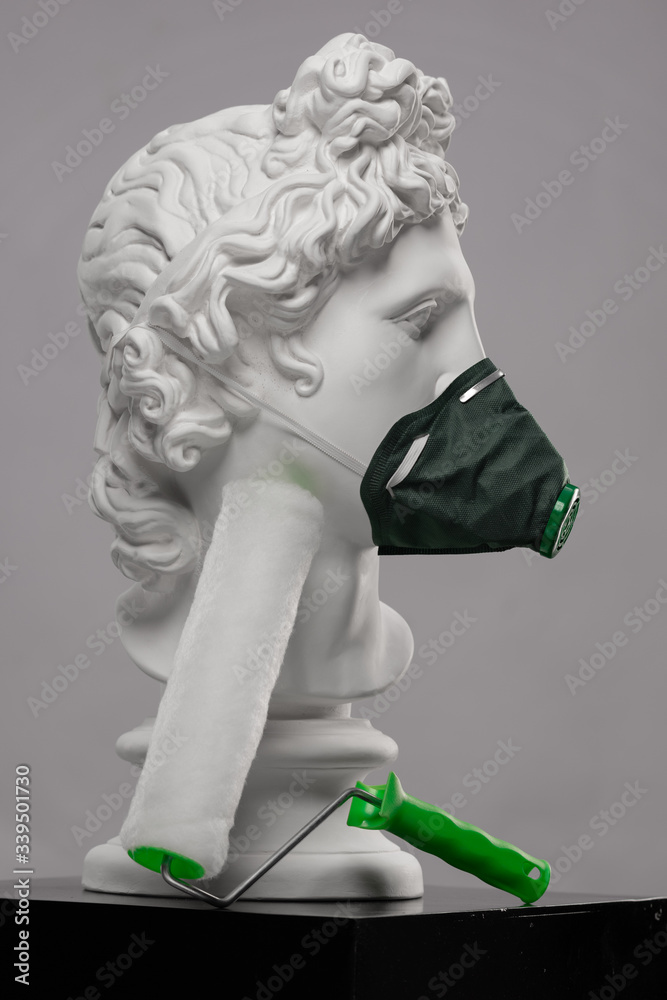 White plaster statue of a bust of Apollo Belvedere in a mask respirator ...
