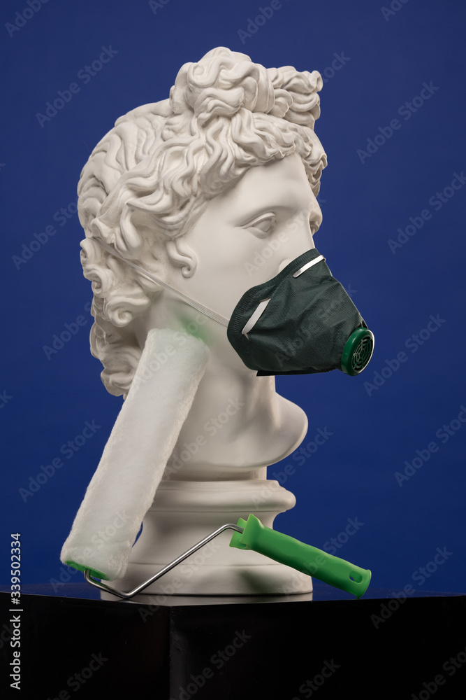 White plaster statue of a bust of Apollo Belvedere in a mask respirator ...