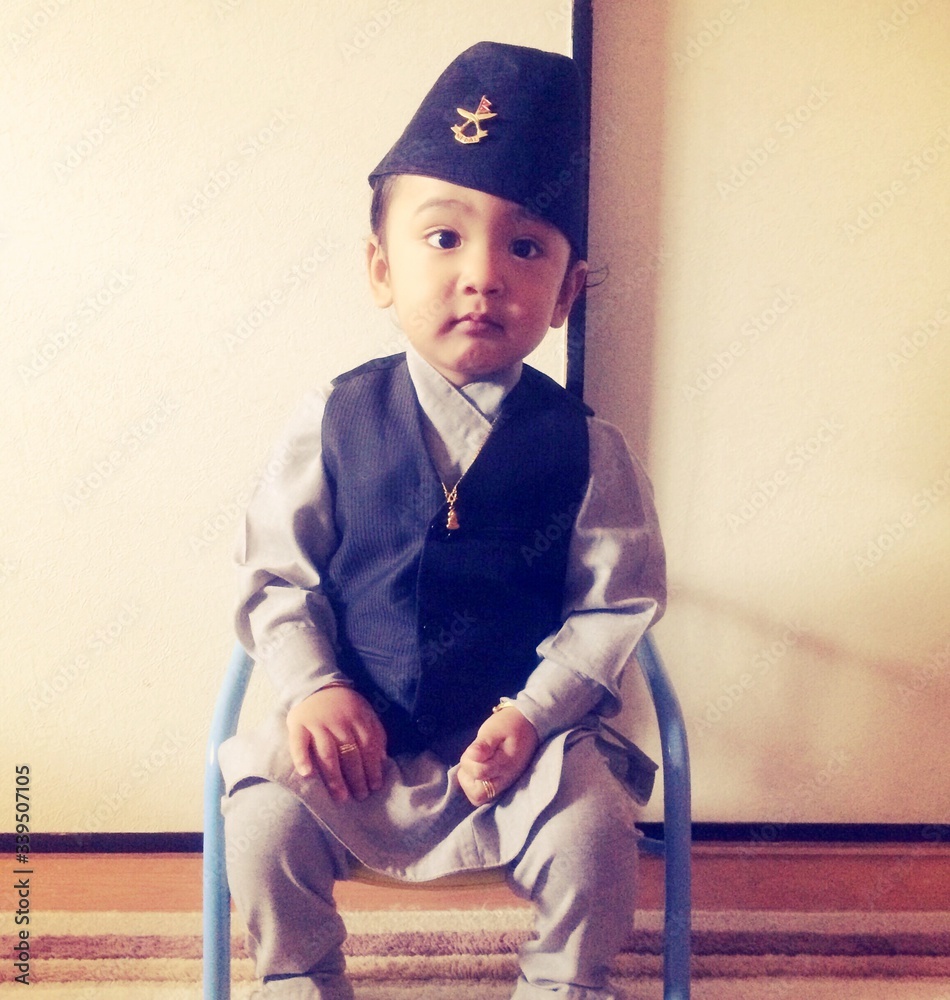 Boy In Traditional Dress Sitting On Chair Against Wall Stock Photo ...