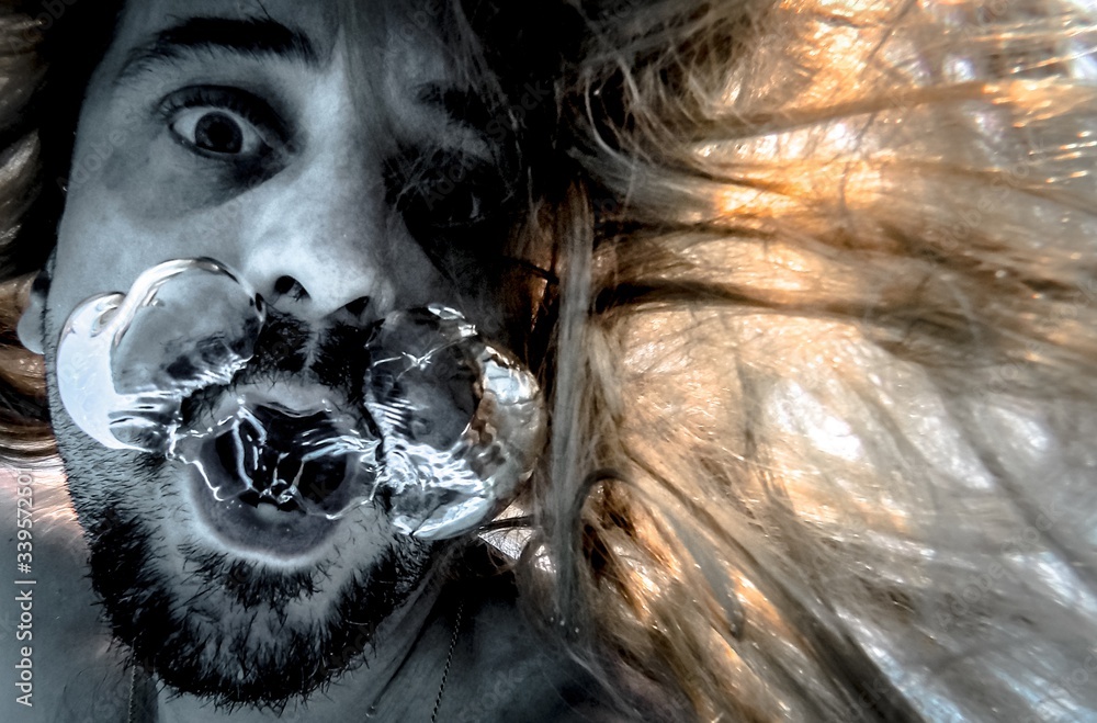 Artistic pic out of focus underwater with long hair man swimming with ...