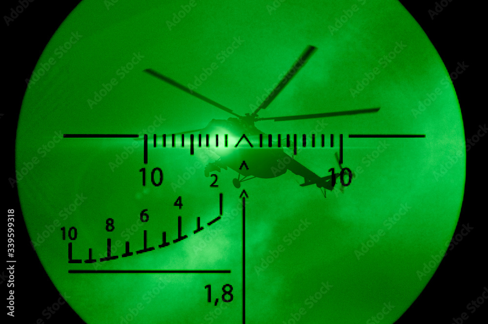 Military helicopter in the optical sight of a sniper rifle. Green light ...