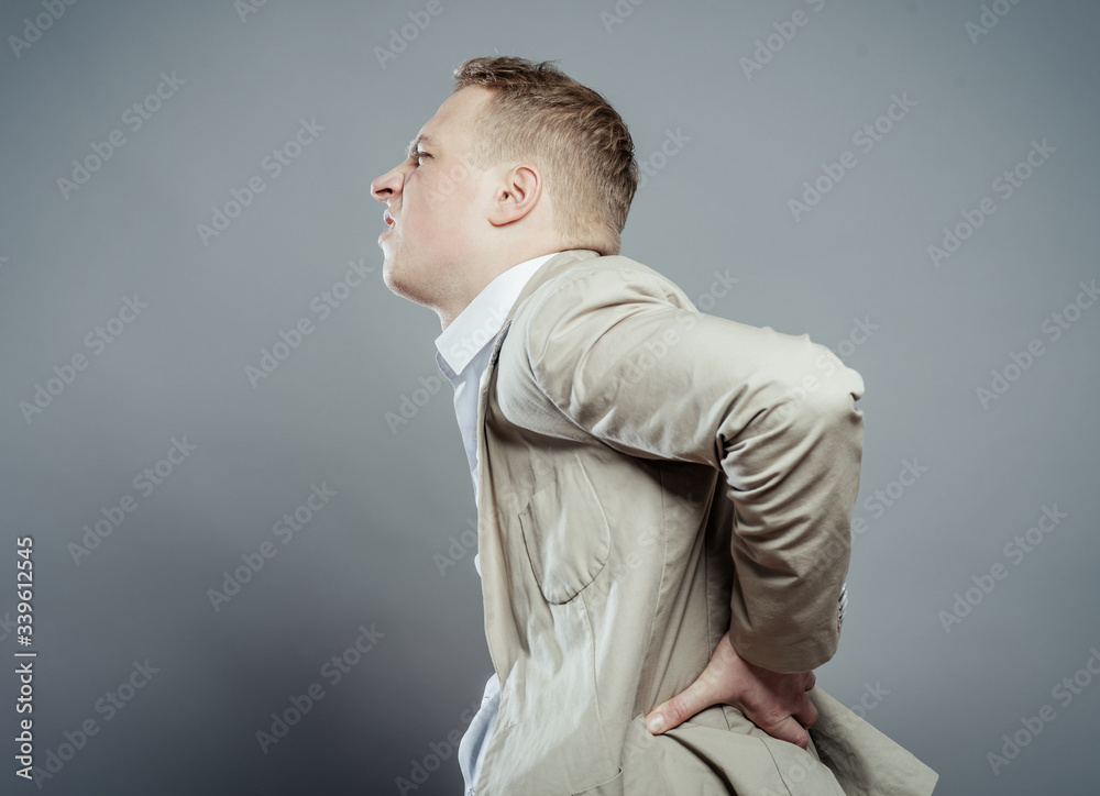 Backache concept bending over in pain with hands holding lower back ...