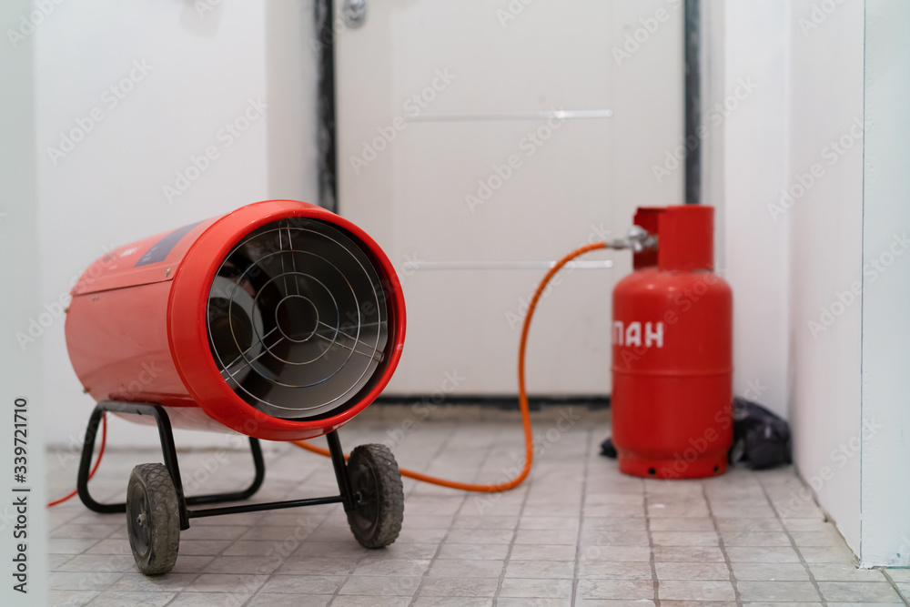 Gas heat gun. Equipment for suspended ceilings. Red tank of propane and ...