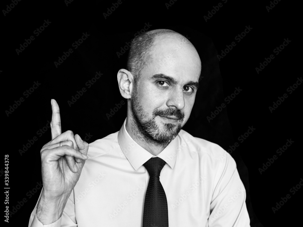 bald spanish man raised his finger up, black and white photo on a dark ...