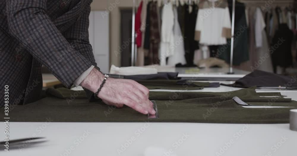 The tailor draws the markings on a fabric with chalk on desktop in ...