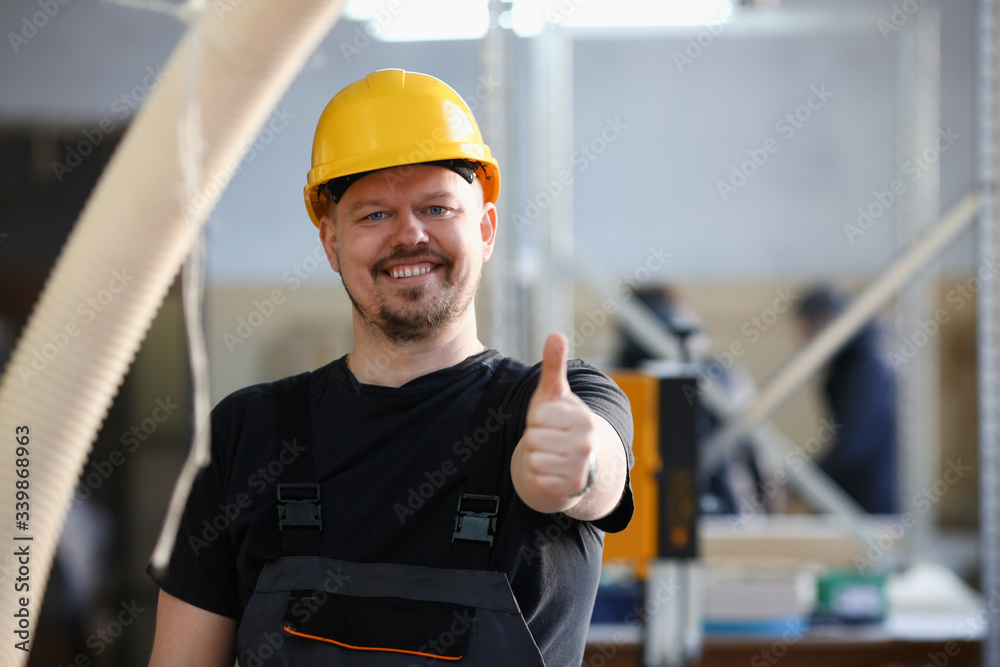 Smiling worker in yellow helmet show confirm sign with thumb up at arm ...
