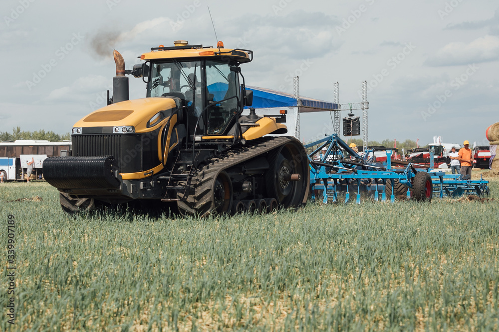 powerful yellow crawler tractor with a trailer for tillage before ...