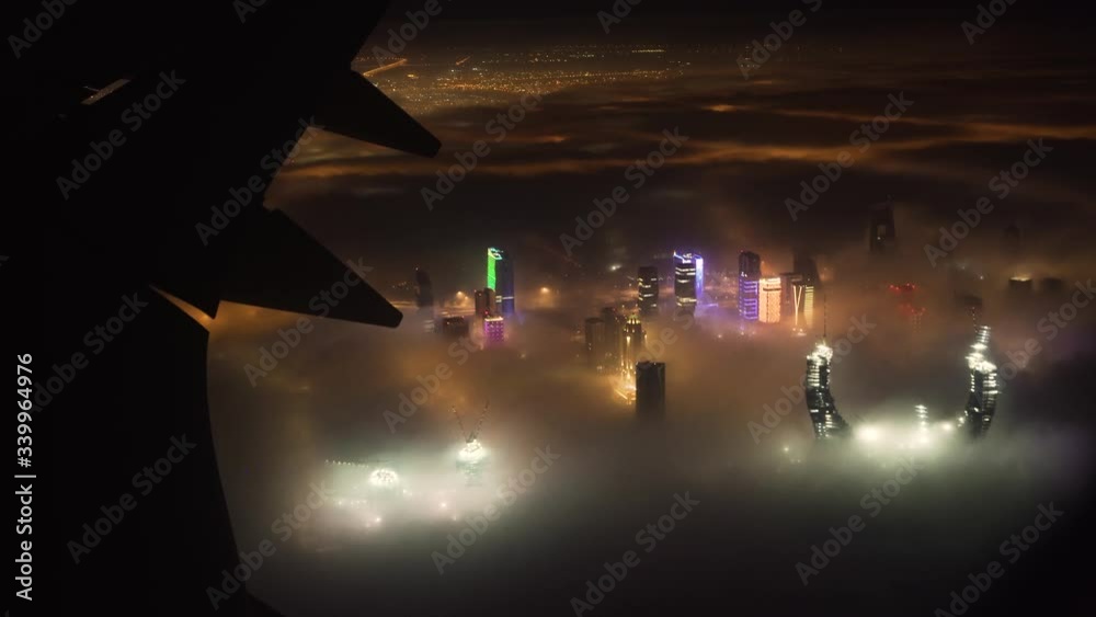 Night flight with fog over the city of Doha Qatar, seen from the window ...