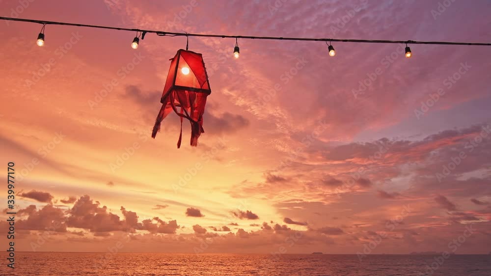Red lantern beach light with lightbulbs are hanging on wired line above ...