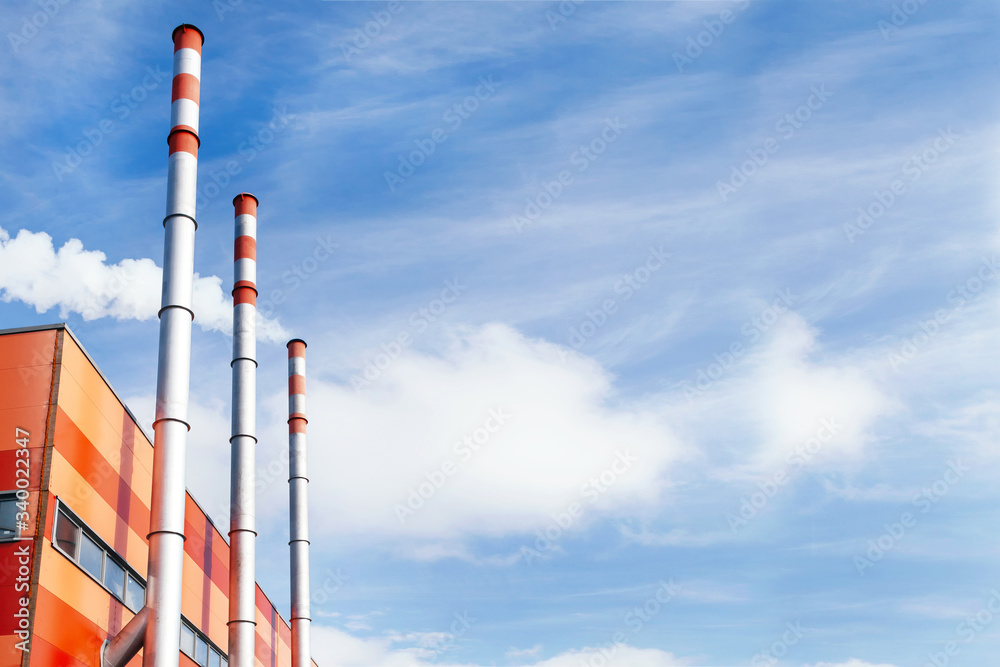 red factory with chimneys and smoke on a background of blue sky and ...