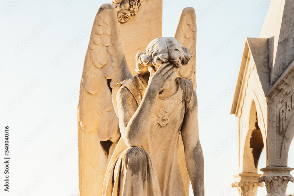 statue of angel with wings against light sky at cemetery. Closing ...