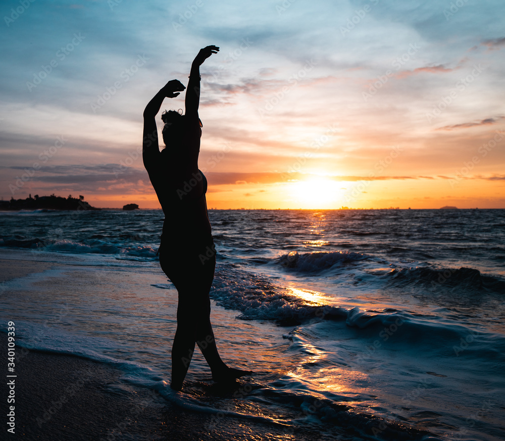 Silueta de mujer en la playa con atardecer Stock Photo | Adobe Stock