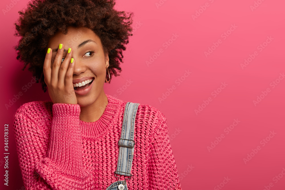 Happy carefree ethnic woman makes face palm, looks happily, hears ...