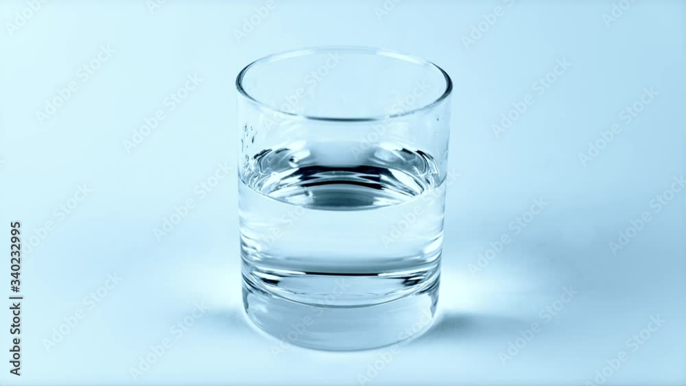Glass cup is filled with water in blue color, stop motion animation ...