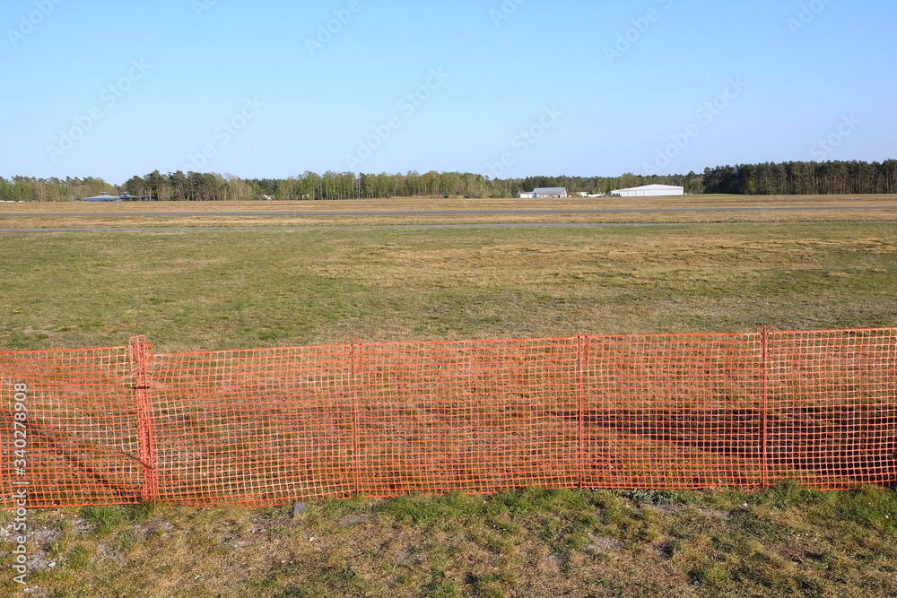 Roter Absperrzaun aus Kunststoff am Flugfeld des Segelflugplatz vor ...